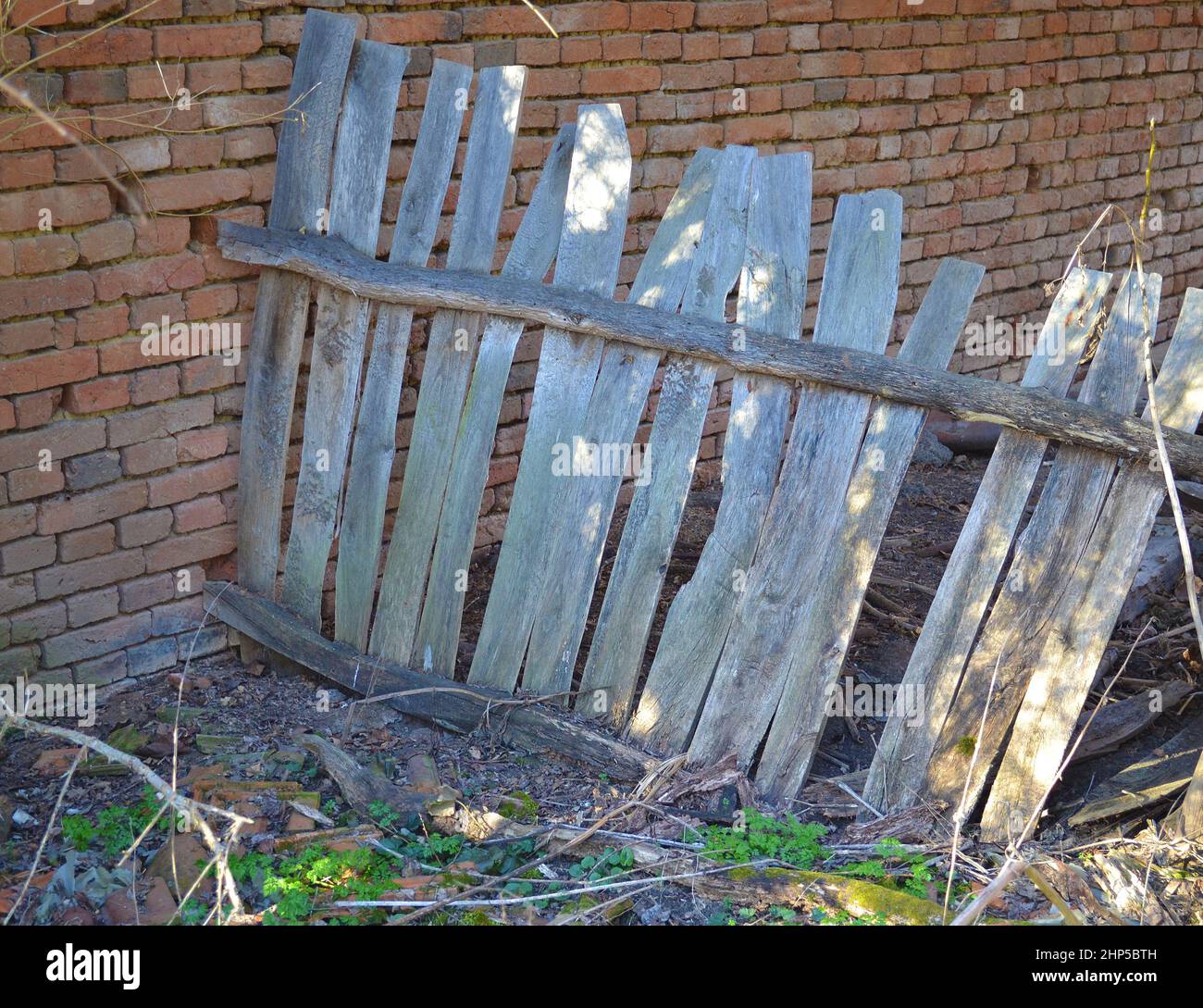 Old broken wooden fence in front of brick wall Stock Photo - Alamy