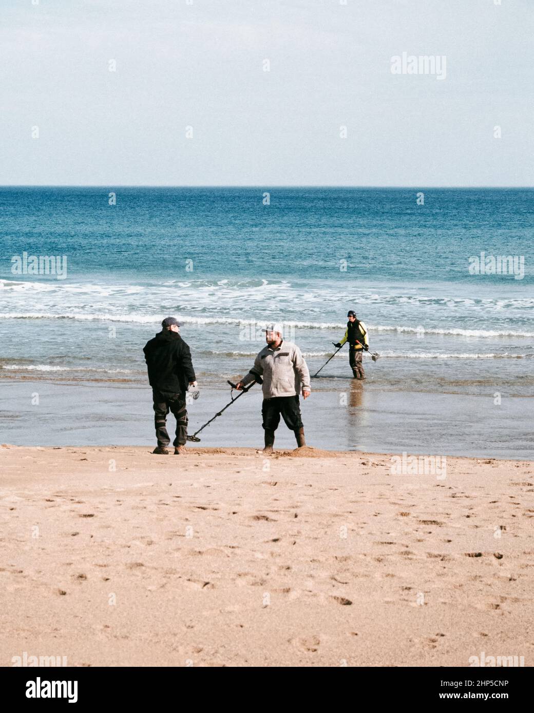 Modern day prospectors scan the shore with metal detectors on a bright ...
