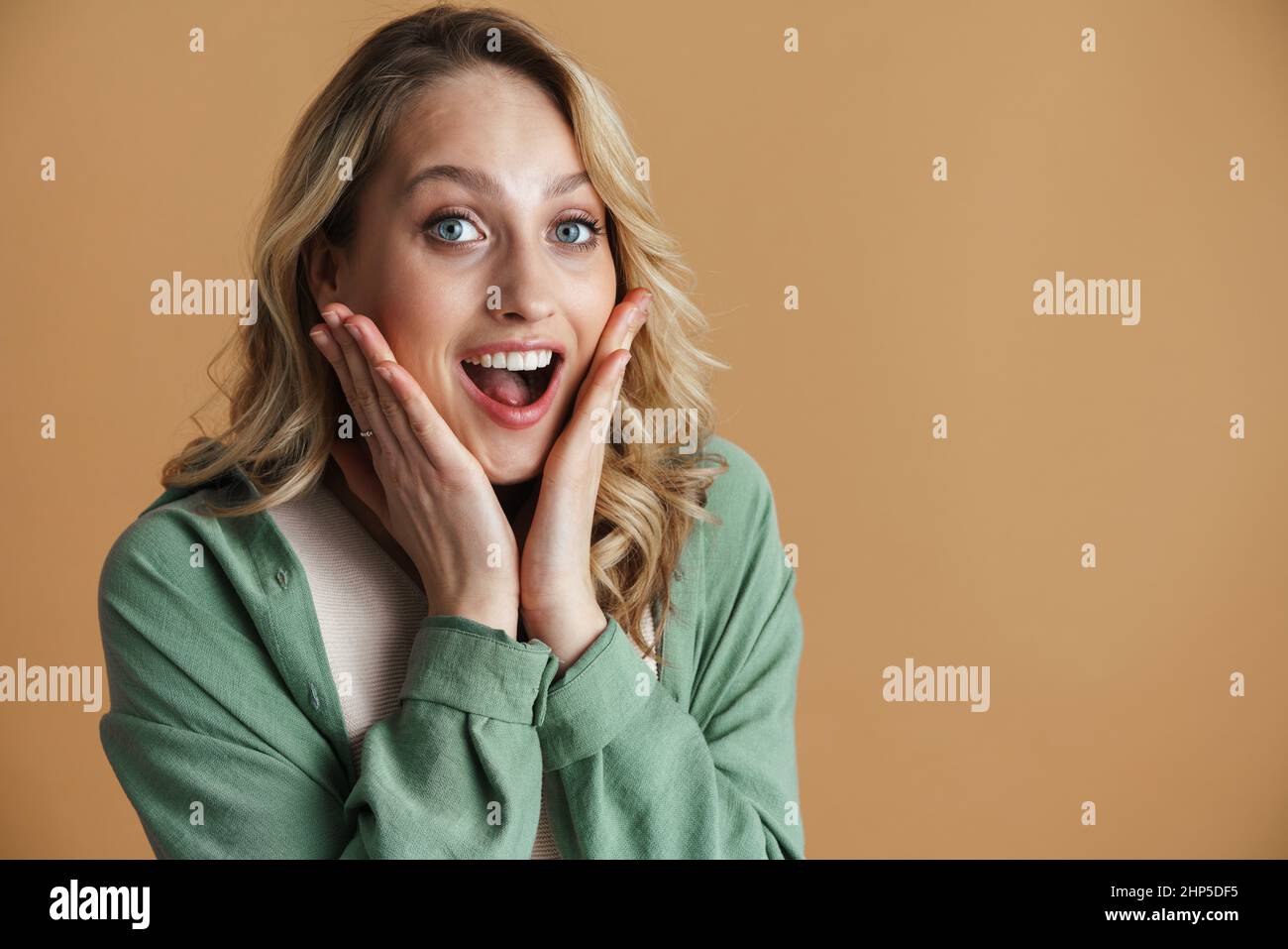 Excited blonde woman expressing surprise at camera isolated over beige wall Stock Photo - Alamy