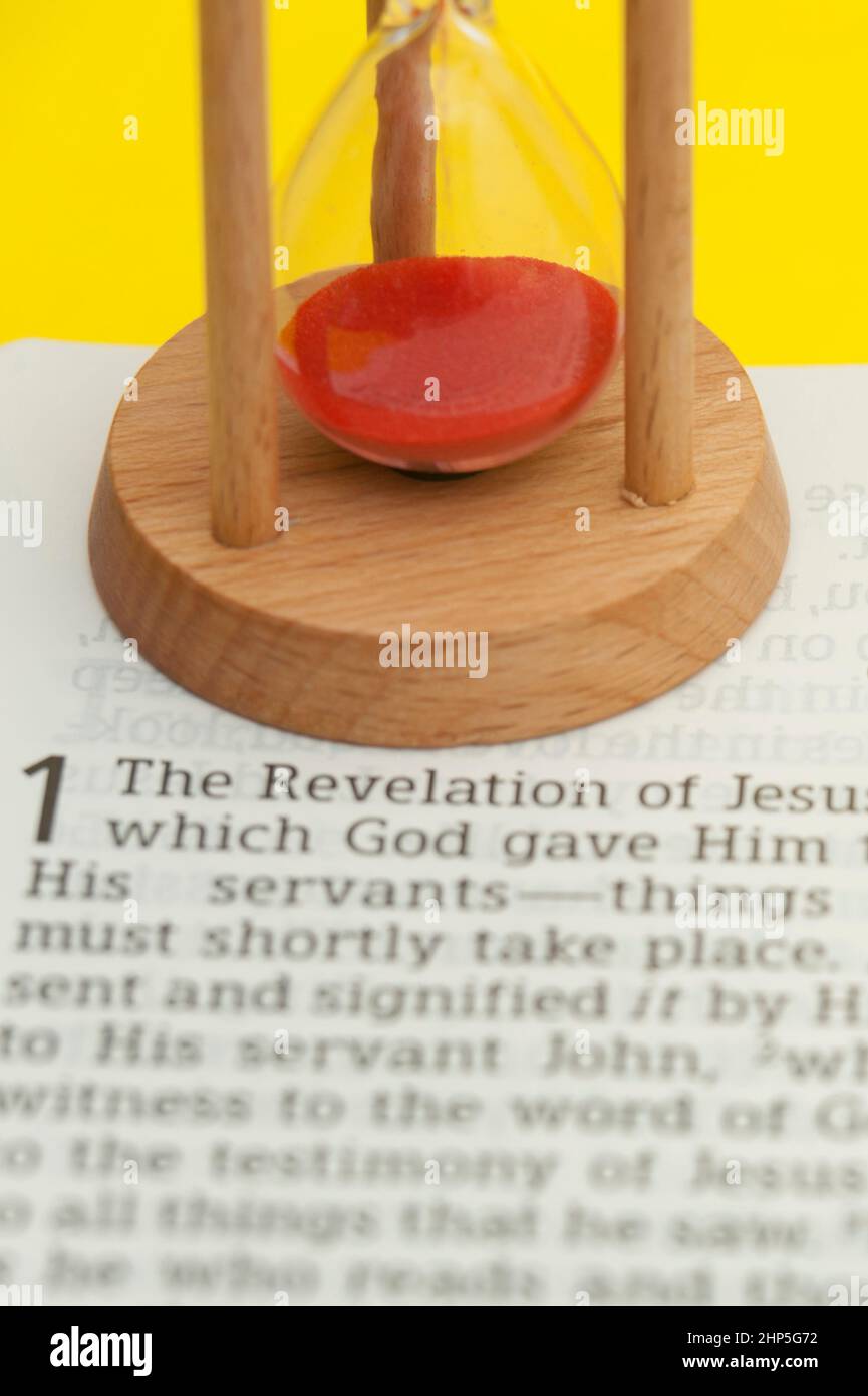 Red sand hourglass on top of Holy Bible opened in Revelation of Jesus ...