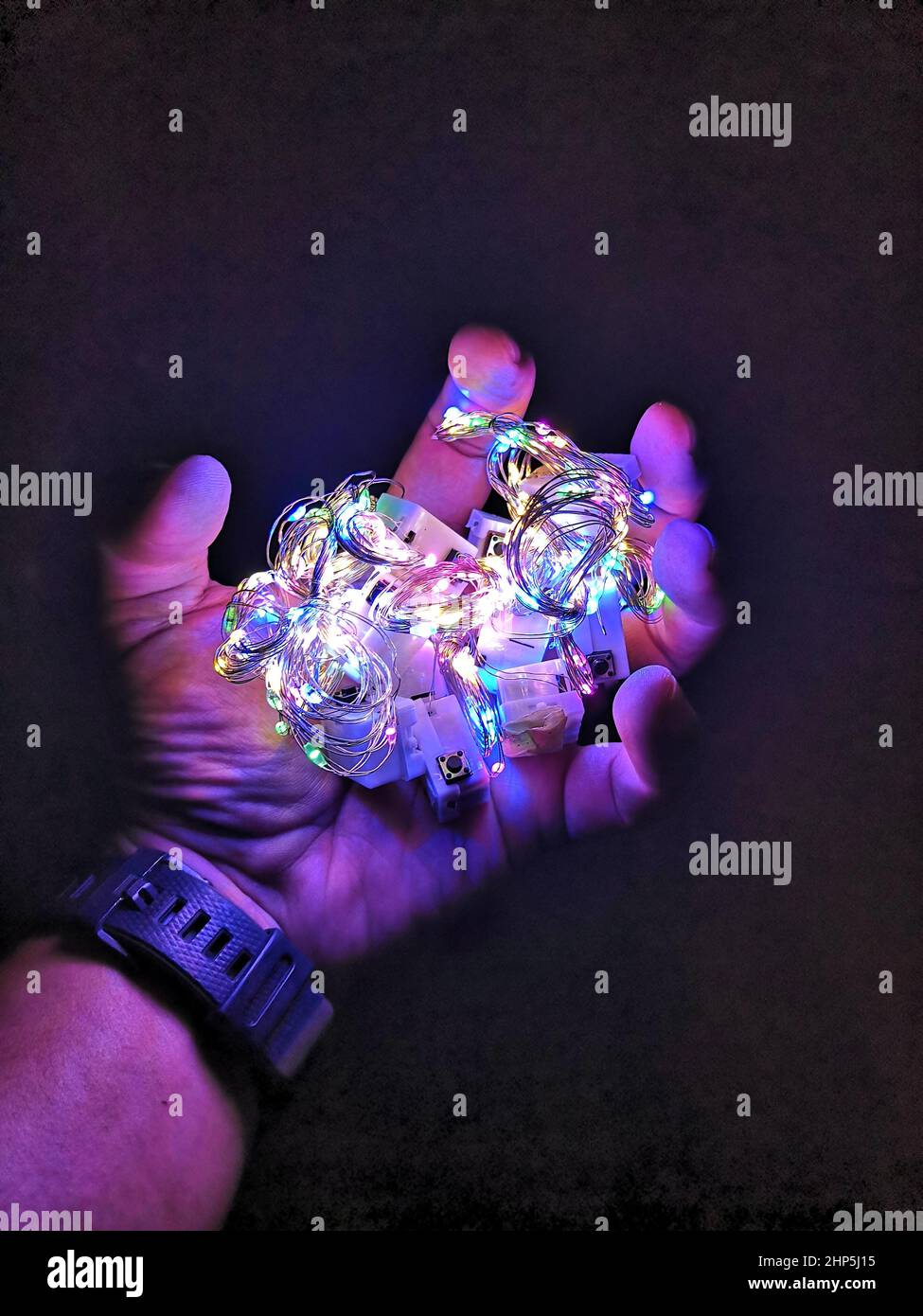Top view of a man's hand holding garland lights wearing a watch Stock ...