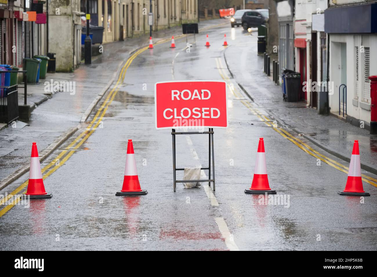 Road ahead closed sign with traffic cones and red barrier fence ...