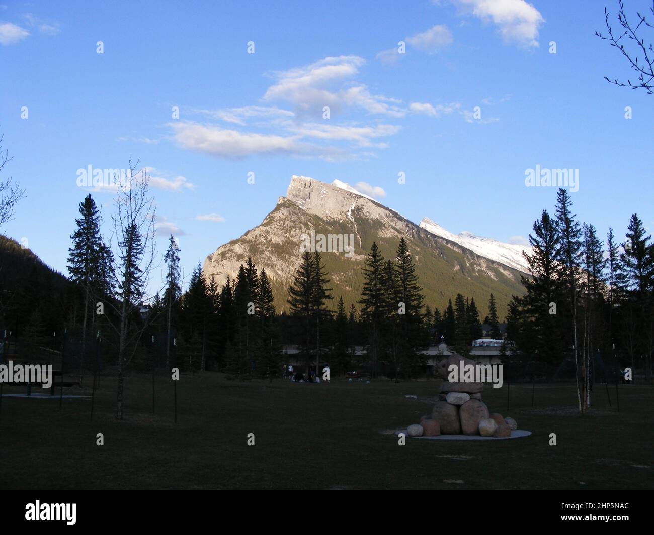 Mt. Rundle peering over trees at small park in Banff at sunset Stock ...