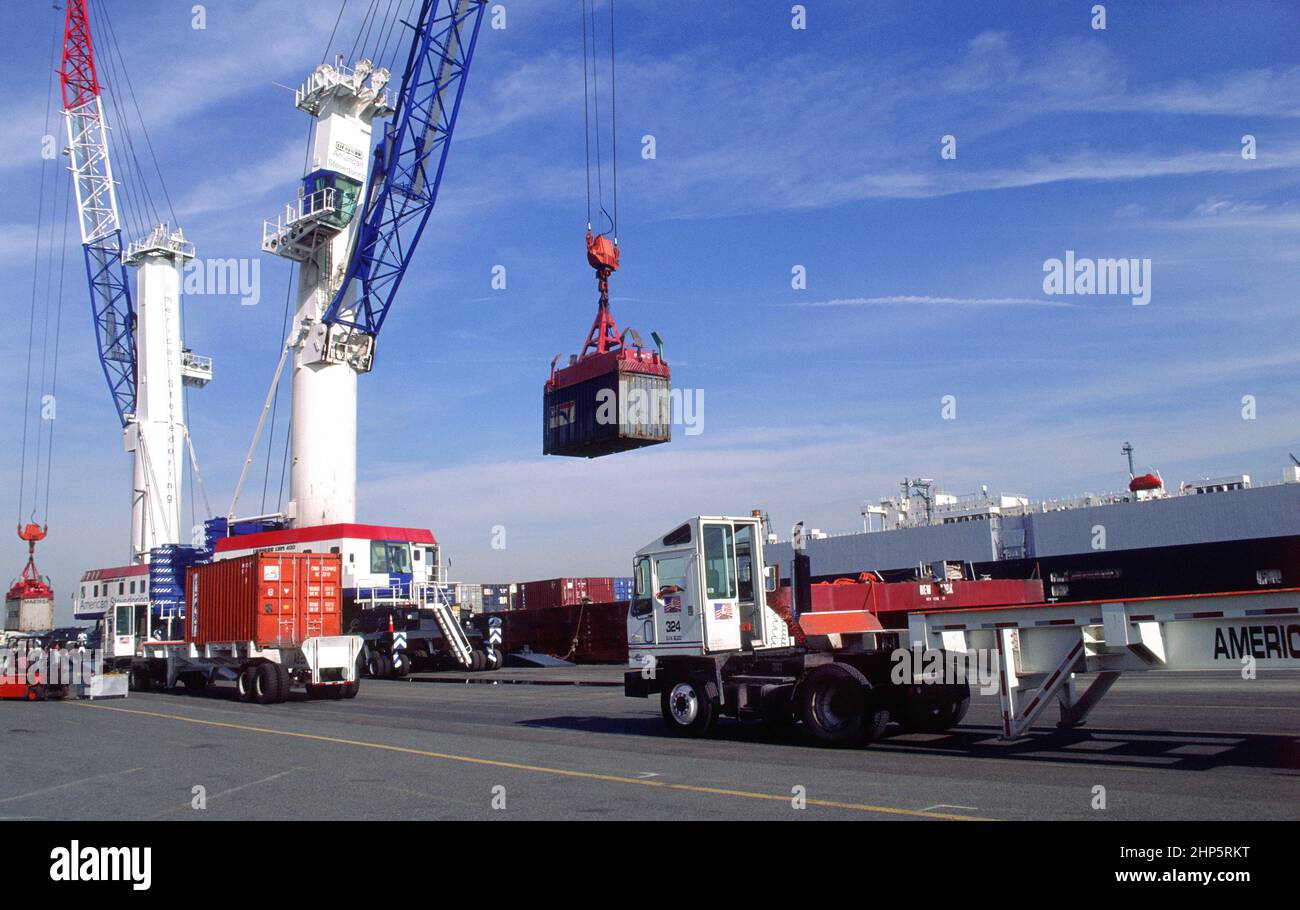 Gantry crane lifting cargo containers onto trucks. Dockside handling ...