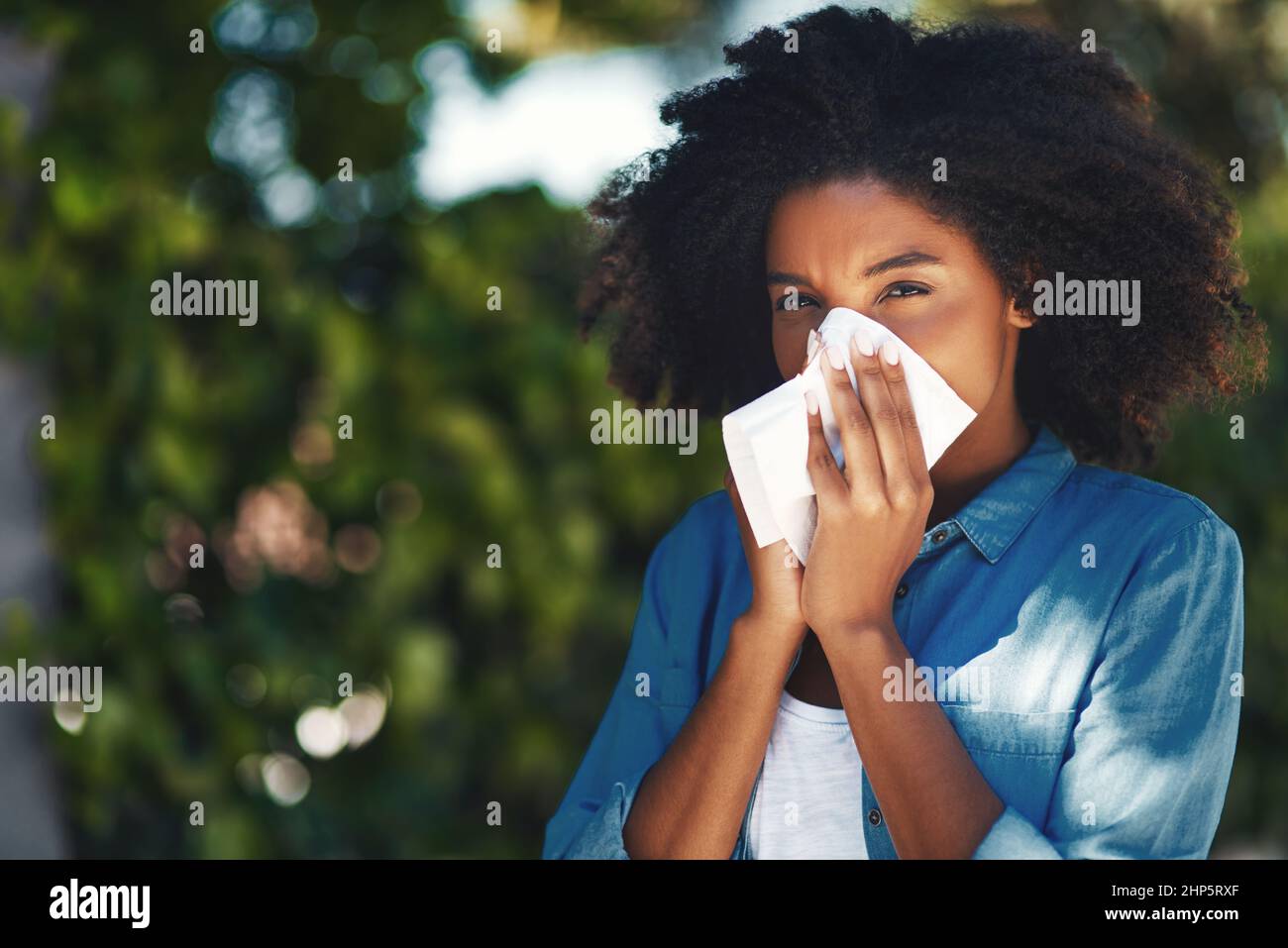 Its the season of sneezes. Portrait of a young woman blowing her nose ...