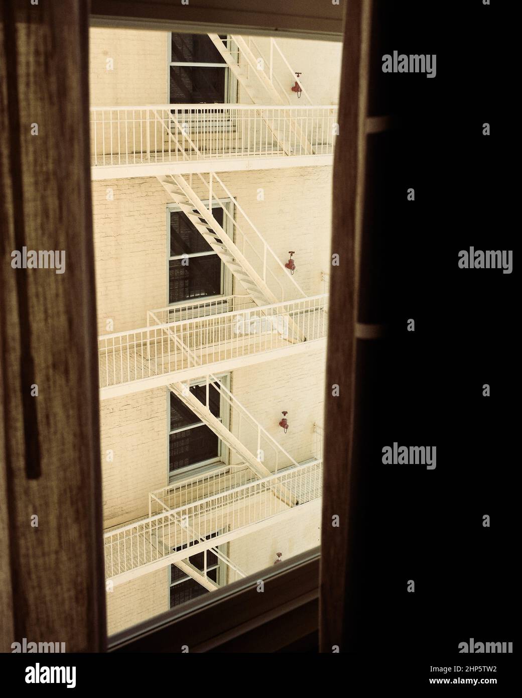 Vertical shot of a white painted fire escape place seen through a ...
