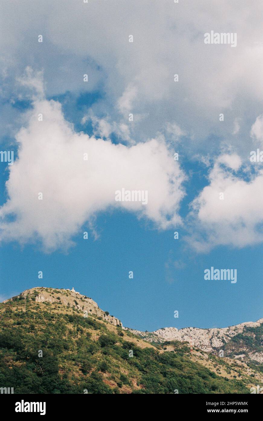 White clouds in the blue sky above the tops of the mountains. Bottom ...