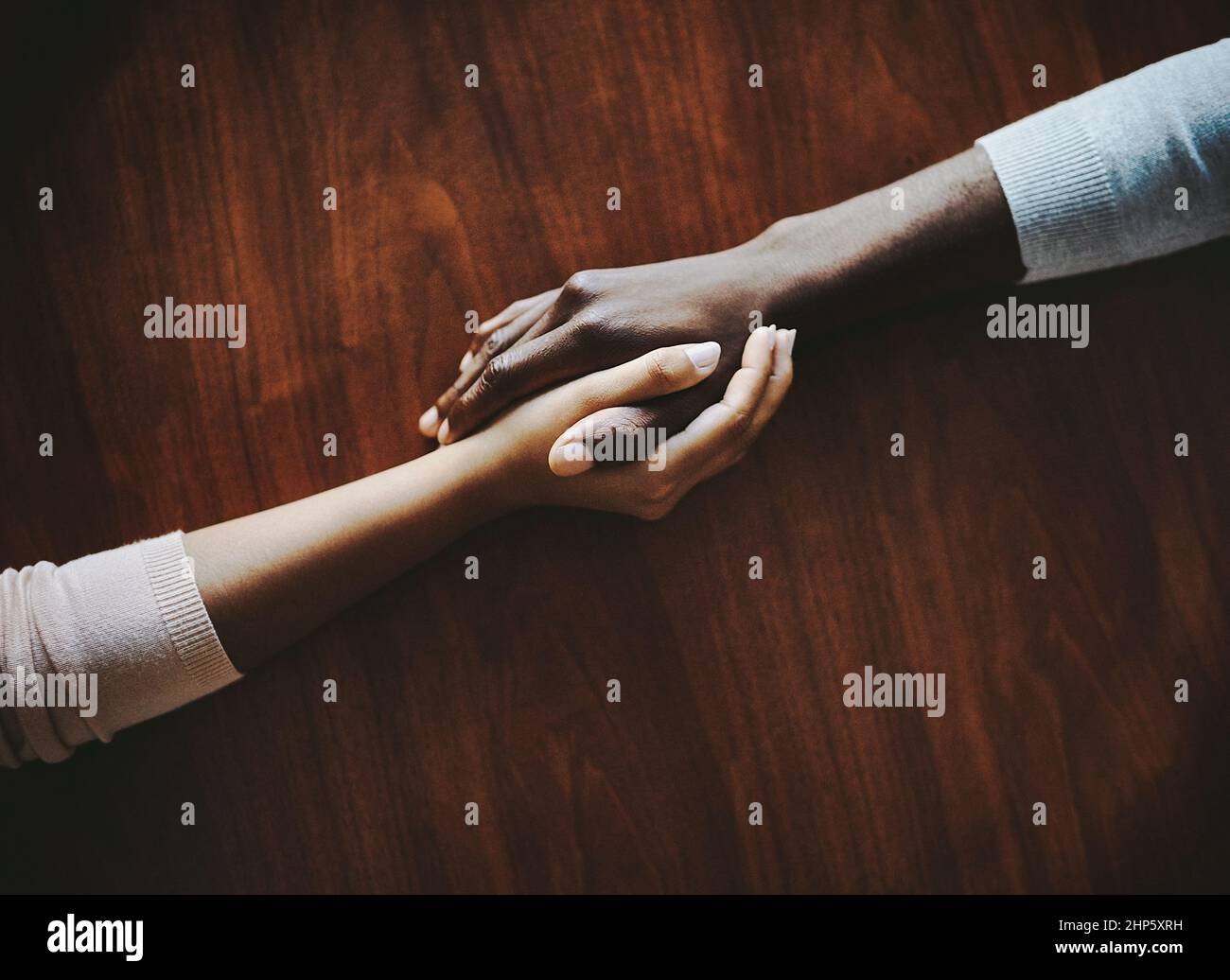 Reaching out in support. High angle shot of two people holding hands in ...