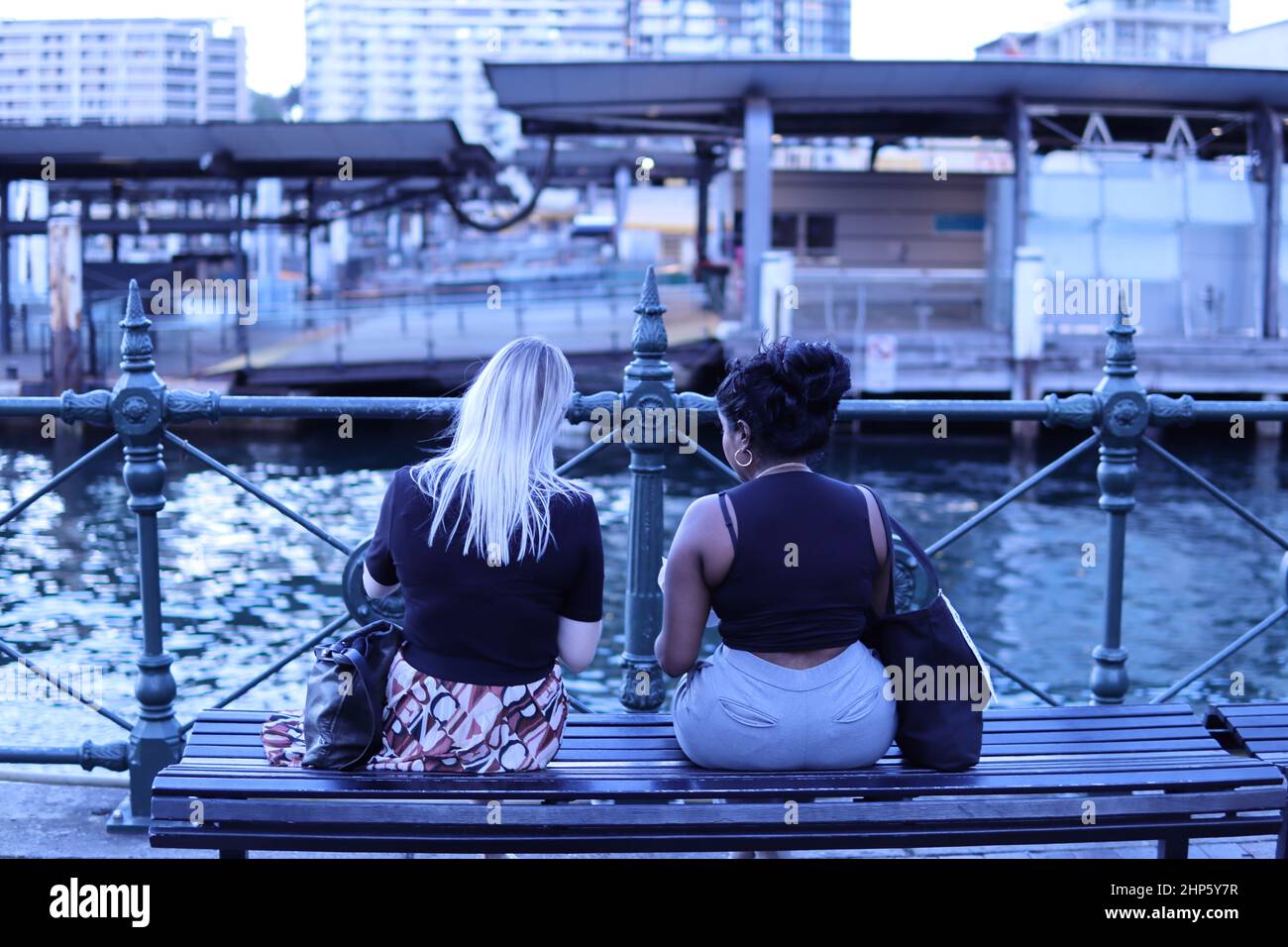 Girls sitting on a banch in a city Stock Photo - Alamy