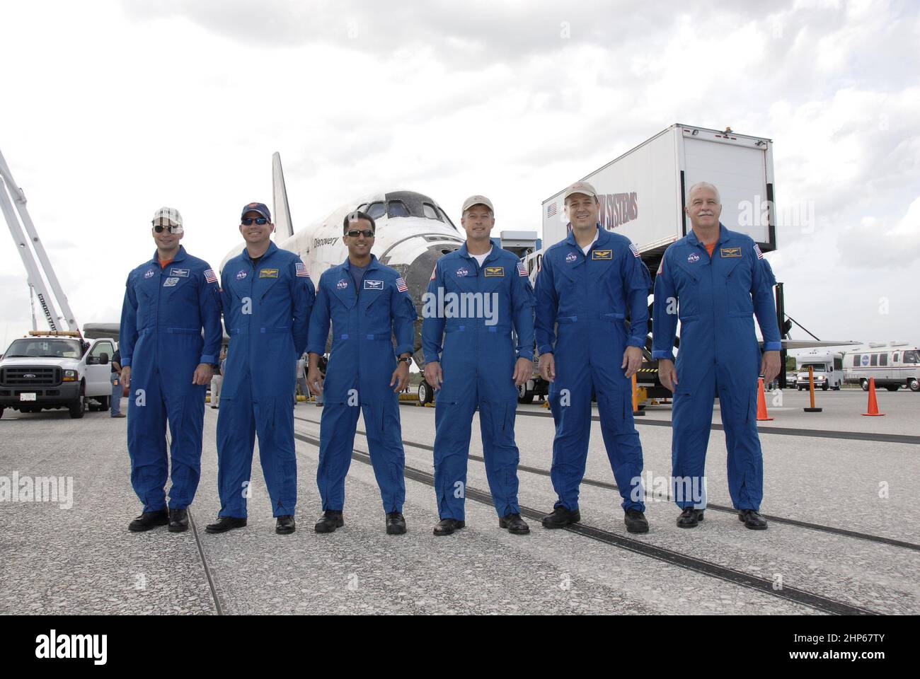 Members of the STS-119 crew pose for a group portrait in front of space ...