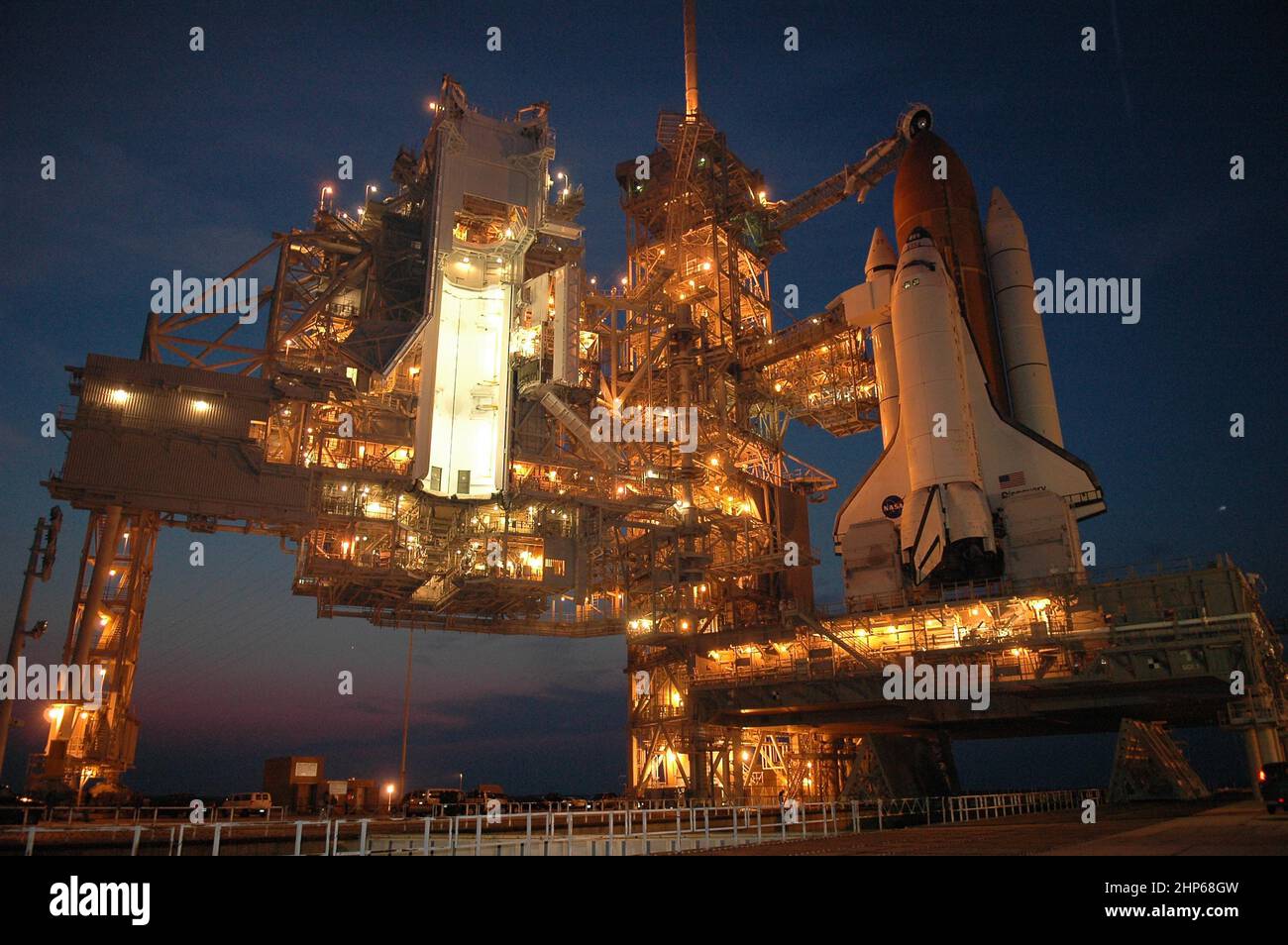 Against a dimming sky after sunset, lights on the structures on Launch ...