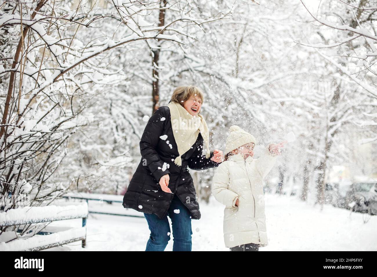Joyful family grandmother with grandchildren in warm clothes playing ...