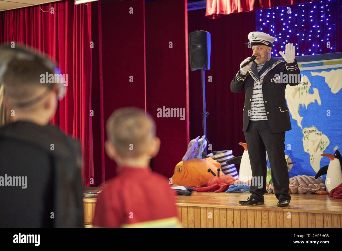 A man dressed as a captain singing on a microphone while standing on ...