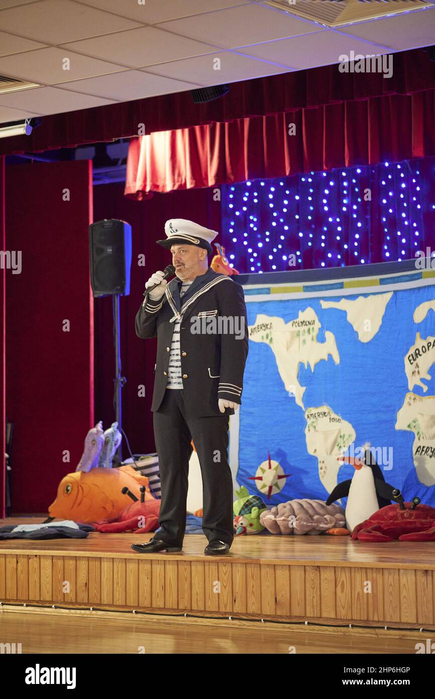 Man dressed as a captain singing on a microphone while standing on ...