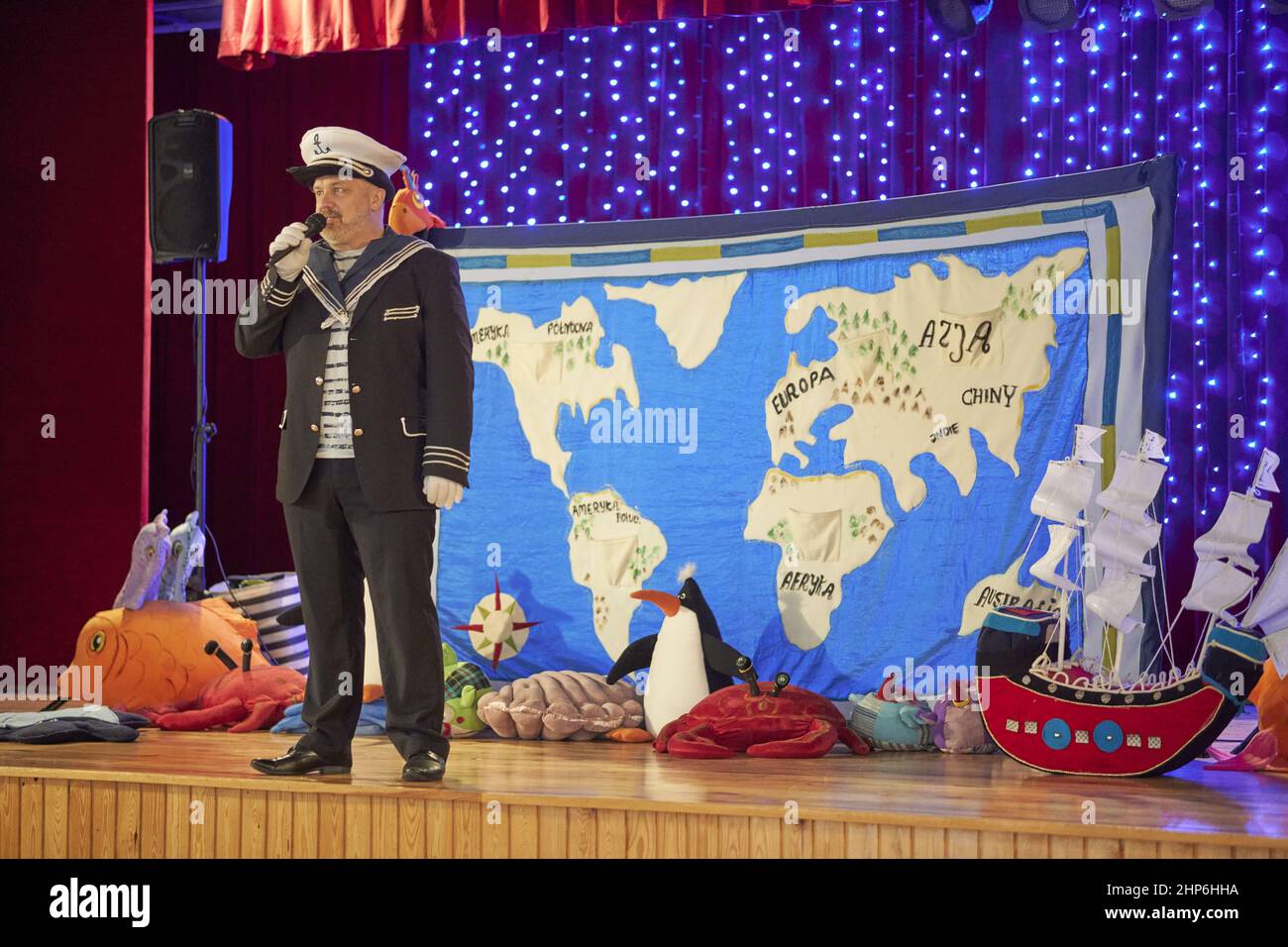 Man dressed as a captain singing on a microphone while standing on ...