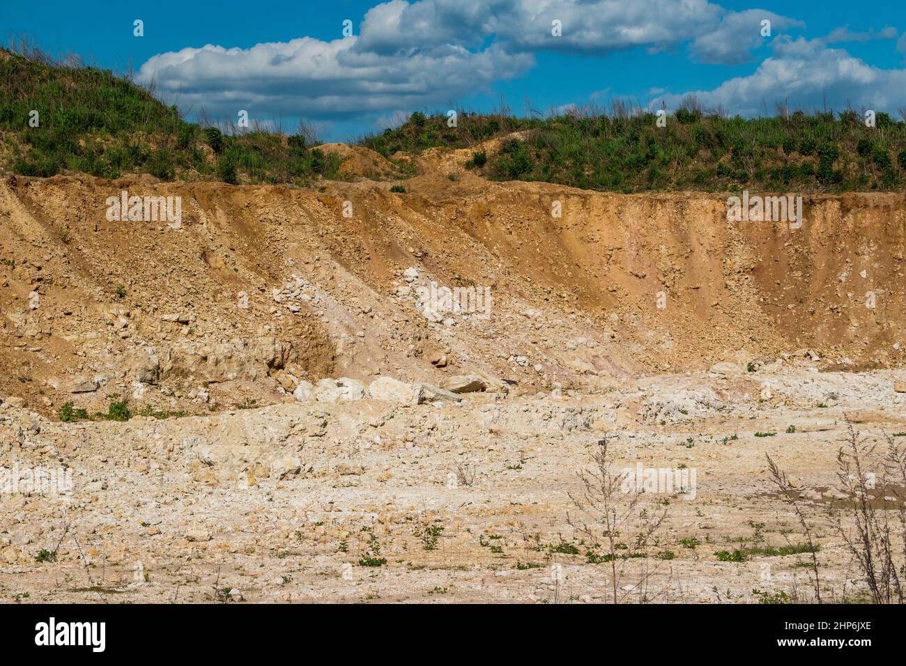 Slope on a limestone quarry, white limestone is covered from above with ...
