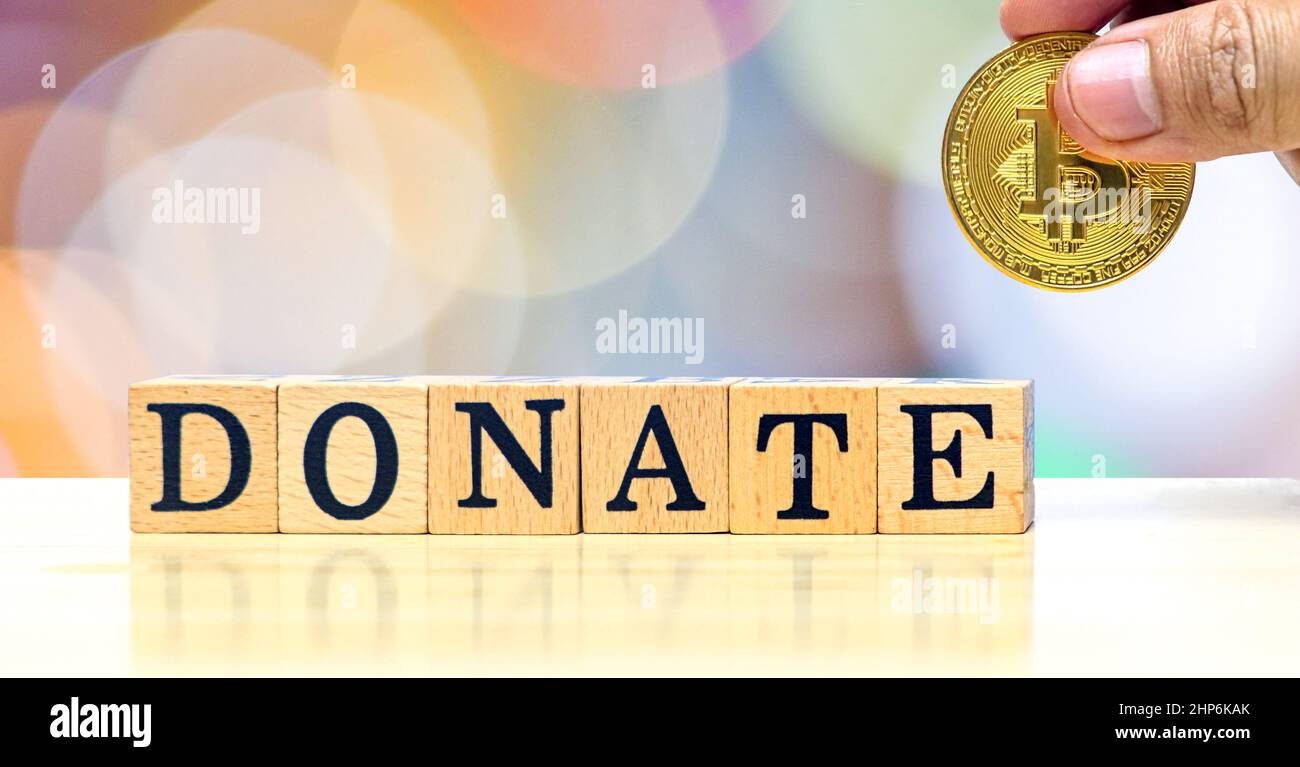 Close-up hands of man who holding gold coin for give to donate wooden ...
