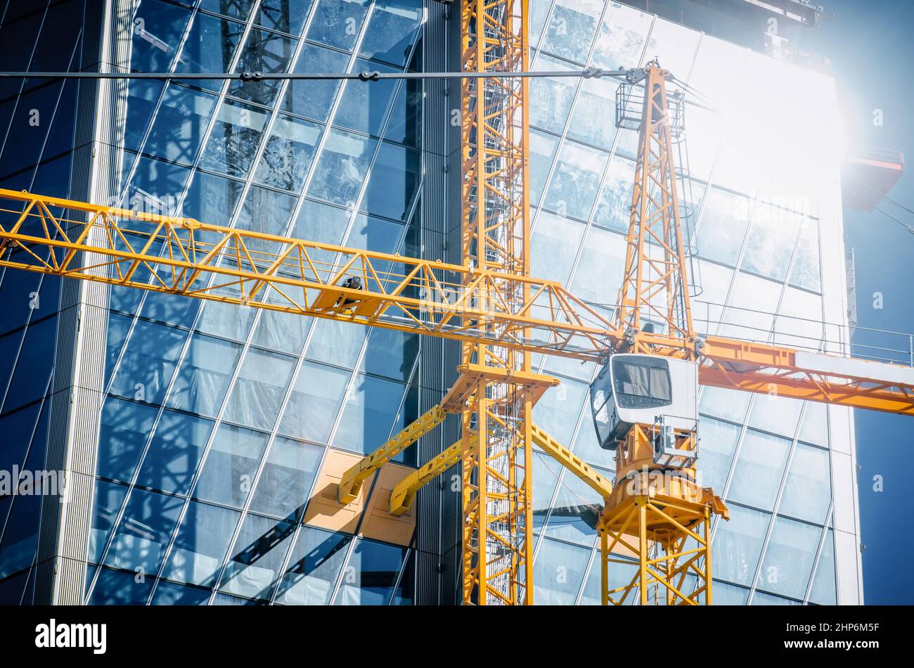 A yellow crane on the background of a glass skyscraper building, with a ...