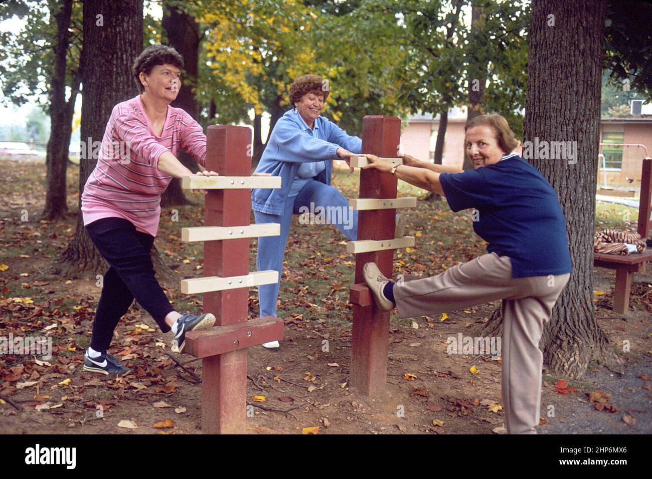 Three older women stretching outdoors before exercising at different ...