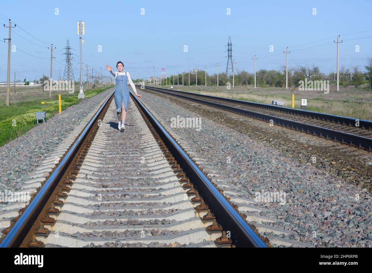 Young woman runs along rails of railroad catches up with train. Lady ...