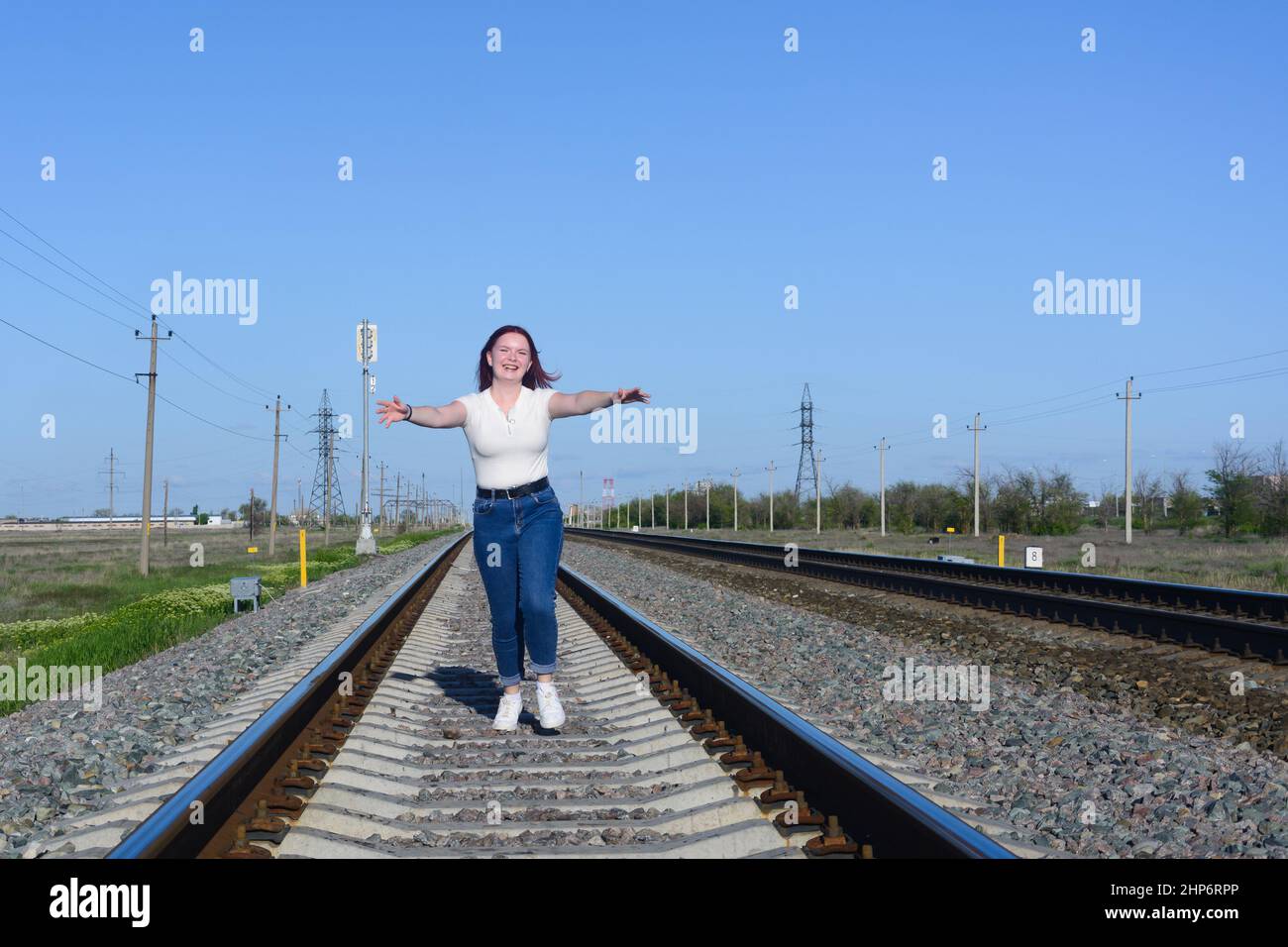 Teenage girl runs along rails of railway ahead of her hands. Lady was ...