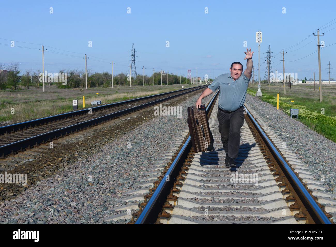 Man with suitcase runs along the railroad tracks. I was late for train ...