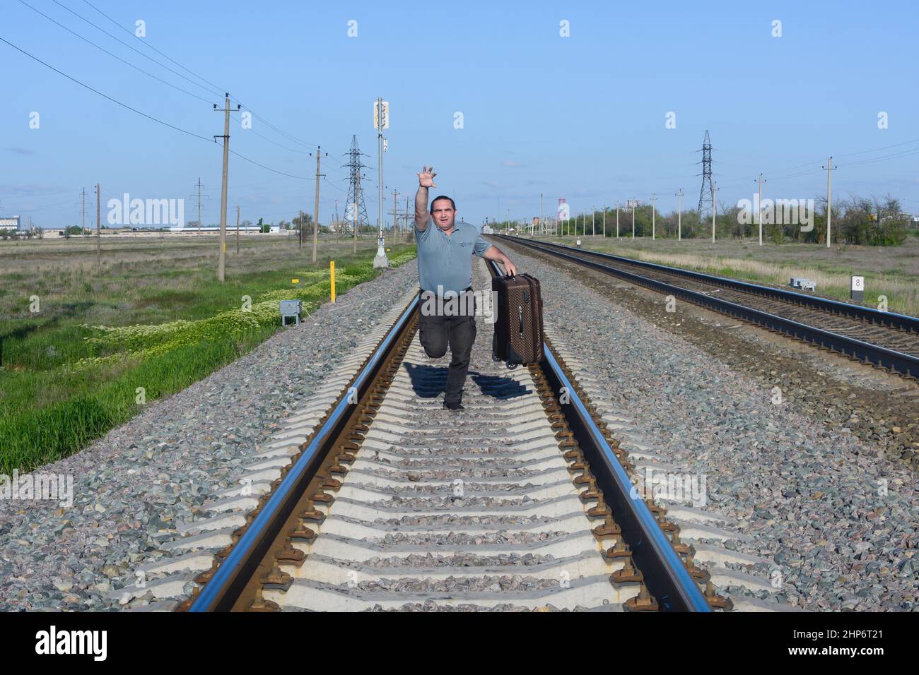 Man with suitcase runs along the railroad. Traveler missed his train ...