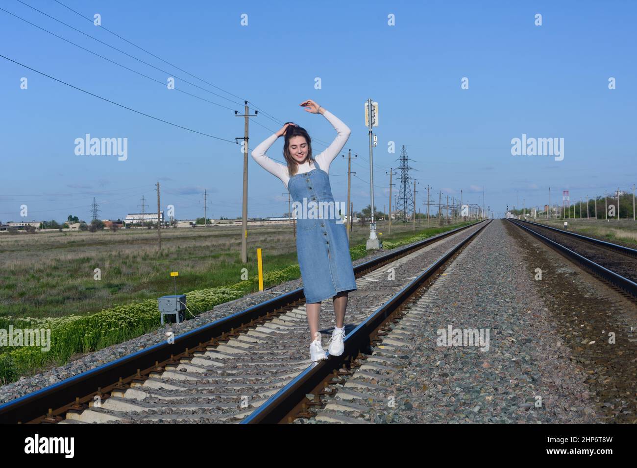 Beautiful woman walks on railroad tracks. Keeps balance by raising his ...