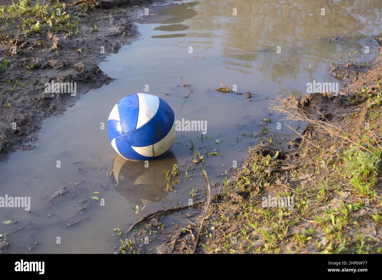 Sports volleyball fell into muddy puddle. Game over Stock Photo - Alamy
