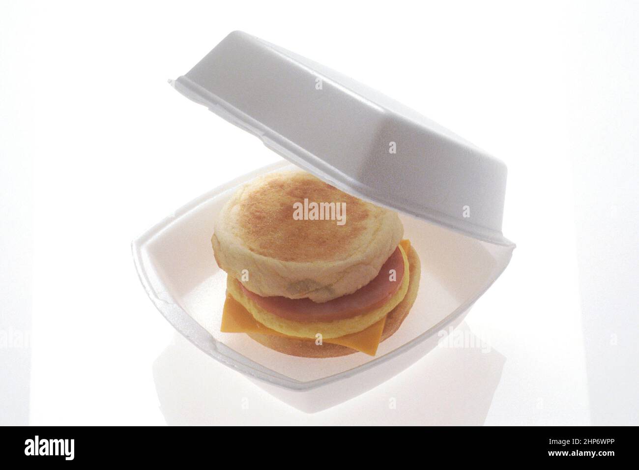An egg, ham and cheese sandwich on english muffin, sitting in a ...