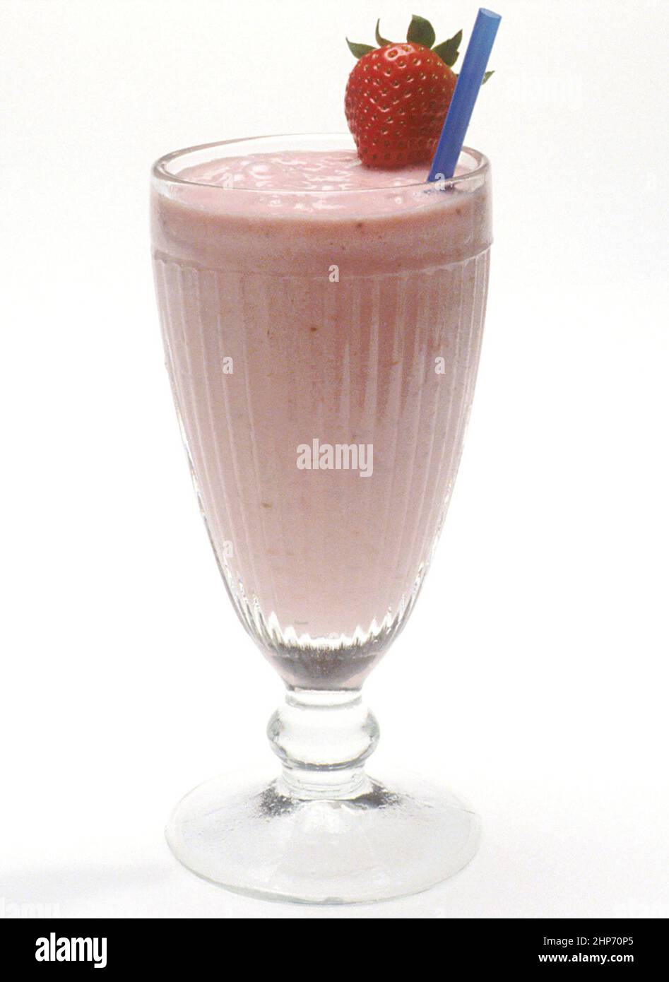A strawberry milk shake in a tall fountain style glass with a straw and ...