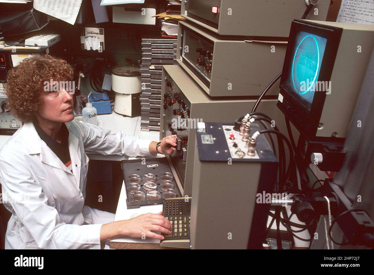A Caucasian female technician operates a plaque counter measuring the ...