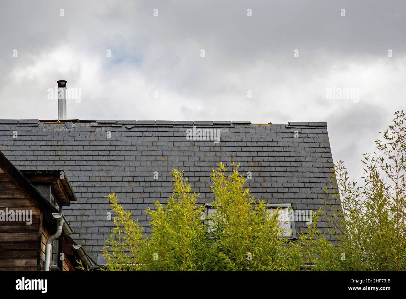 A house roof with damaged and missing ridge tiles pictured on a stormy ...