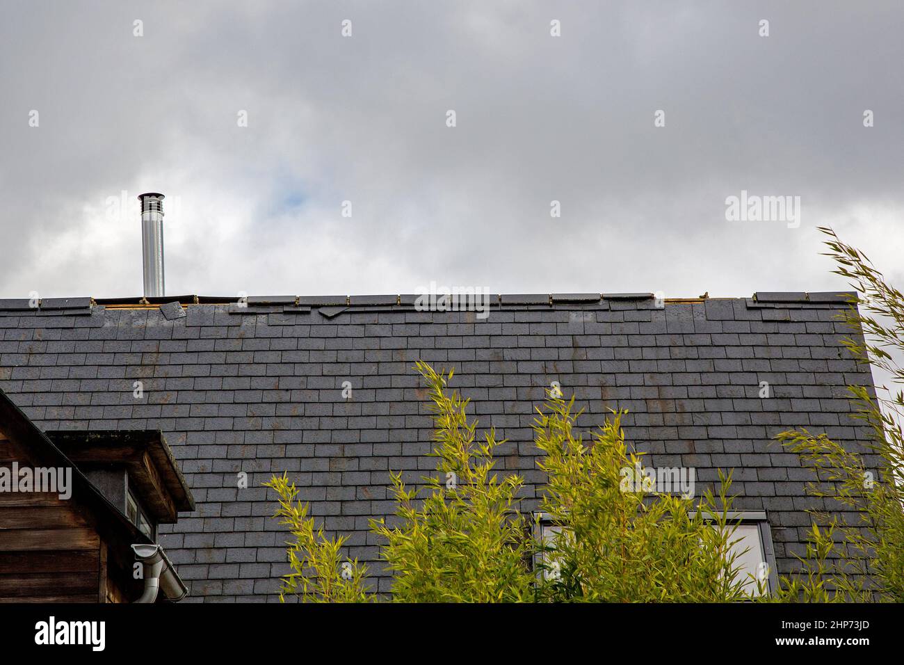 A house roof with damaged and missing ridge tiles pictured on a stormy ...