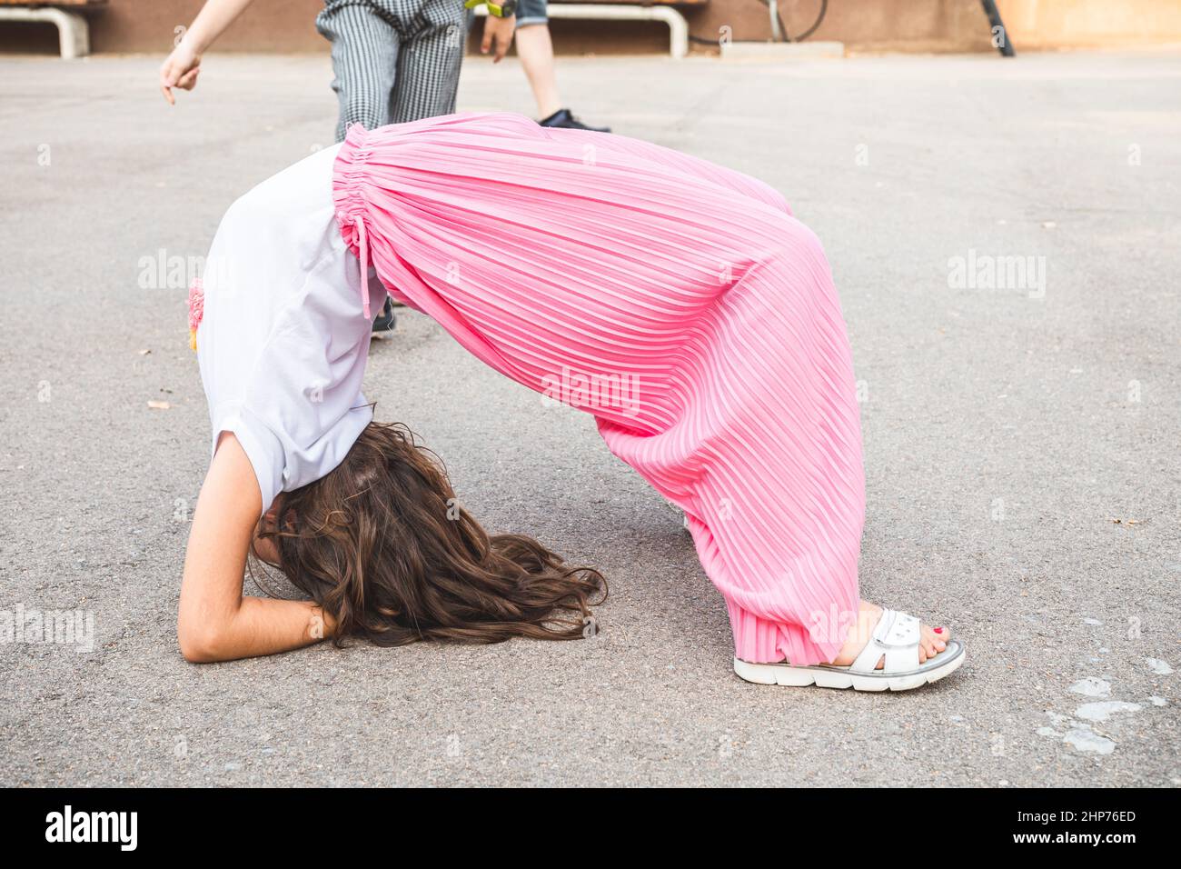 Little brunette girl smiling and making bridge pose outdoors Stock ...