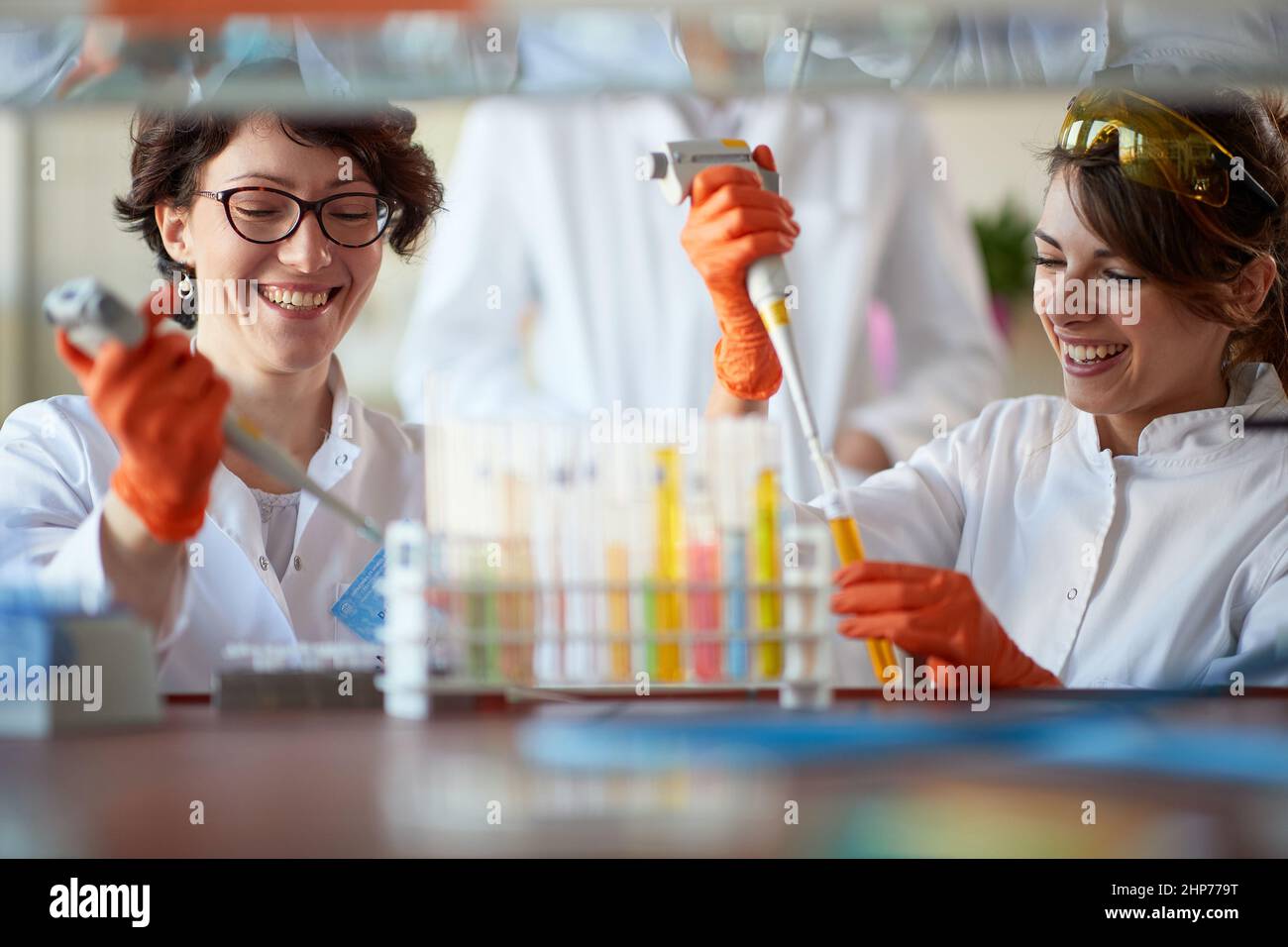Young female chemistry students enjoy while pipetting colourful ...
