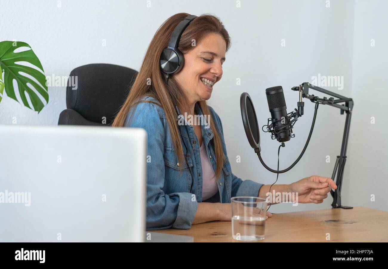 Mature woman recording a podcast using microphone and laptop from her ...