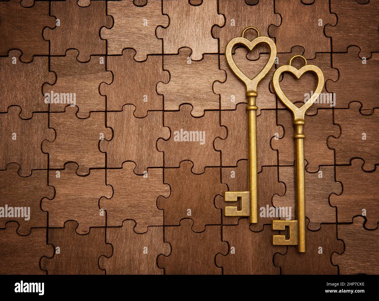Two retro style bronze toned heart shaped keys on a jigsaw puzzle ...