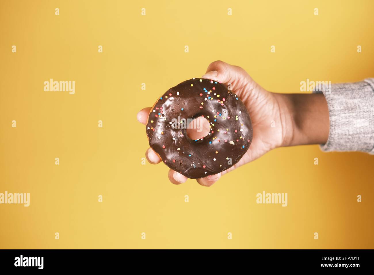 Close up of hand holding donuts against yellow background Stock Photo ...