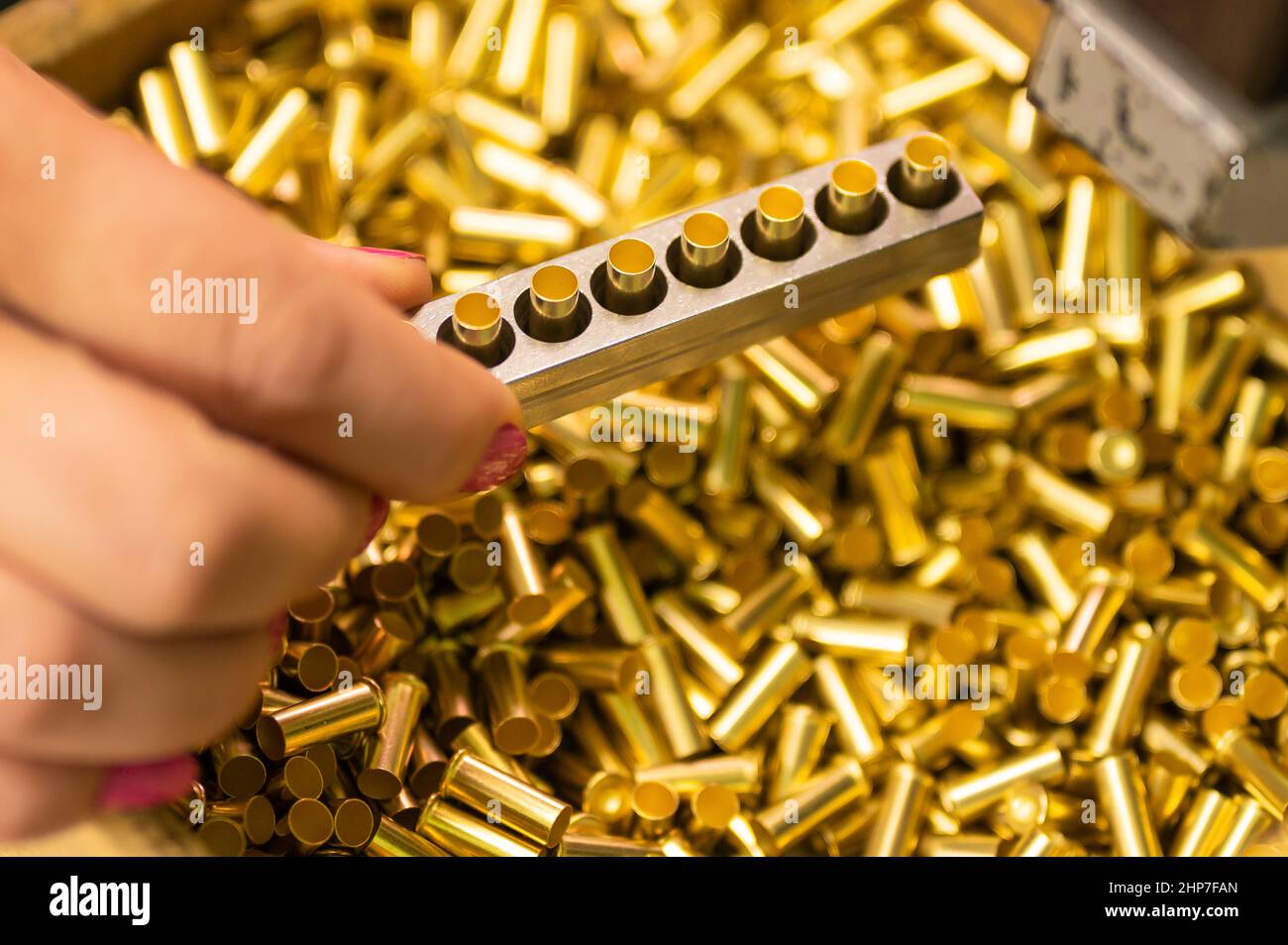 Woman holds bar with new golden bullet shells over container Stock ...