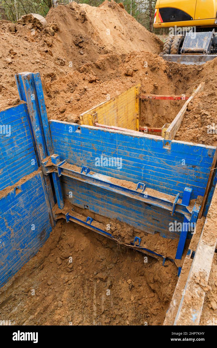 Installation of metal supports to protect the walls of the trench. The ...