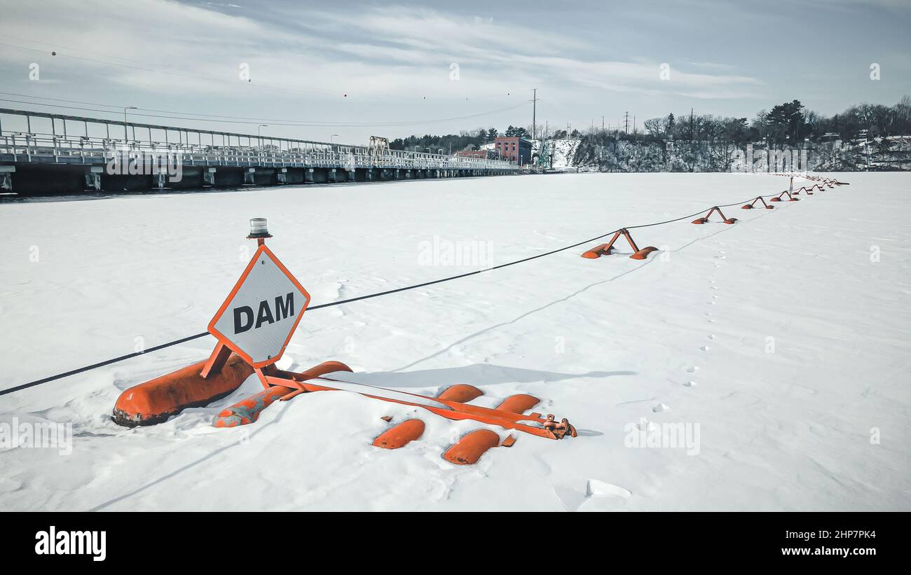 The lake is frozen with the edge of water flowing into the dam Stock ...