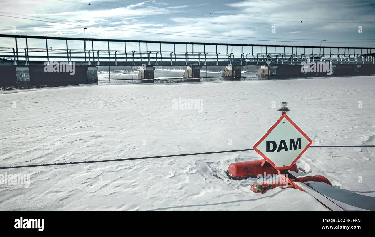 The lake is frozen with the edge of water flowing into the dam Stock ...