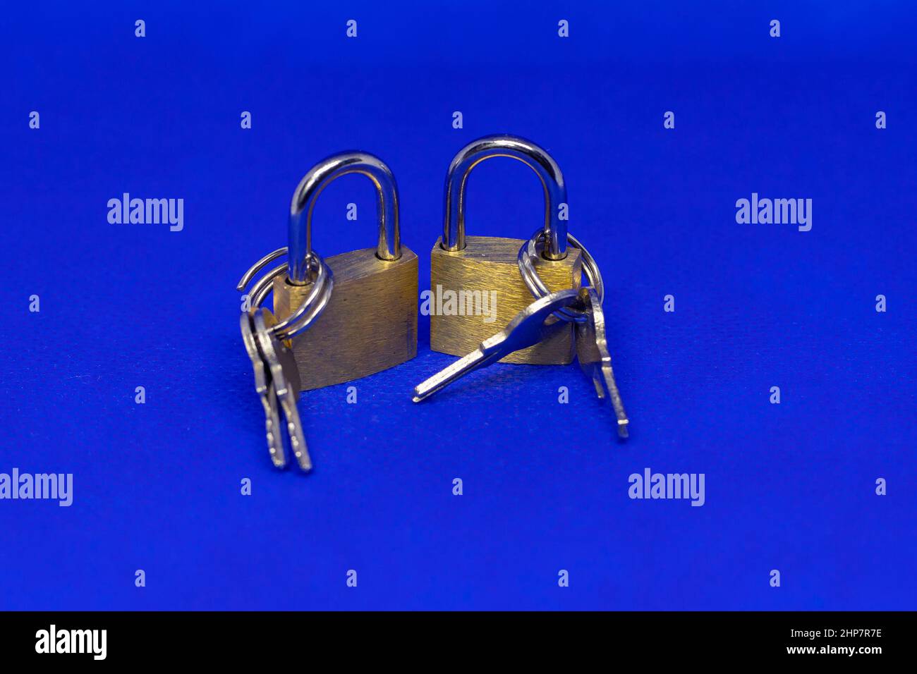 Two small padlocks with two keys. The photo has a blue background Stock ...