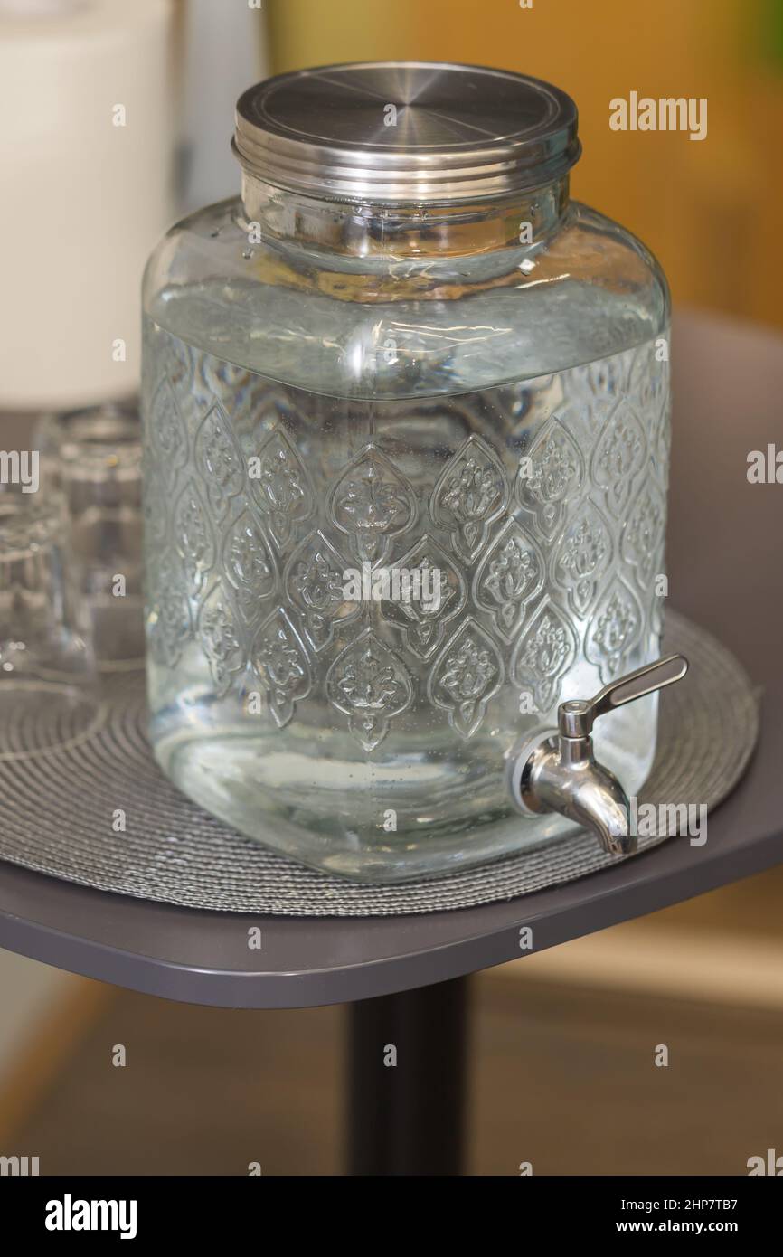 Homemade glass water container stands on the table. The container has a ...