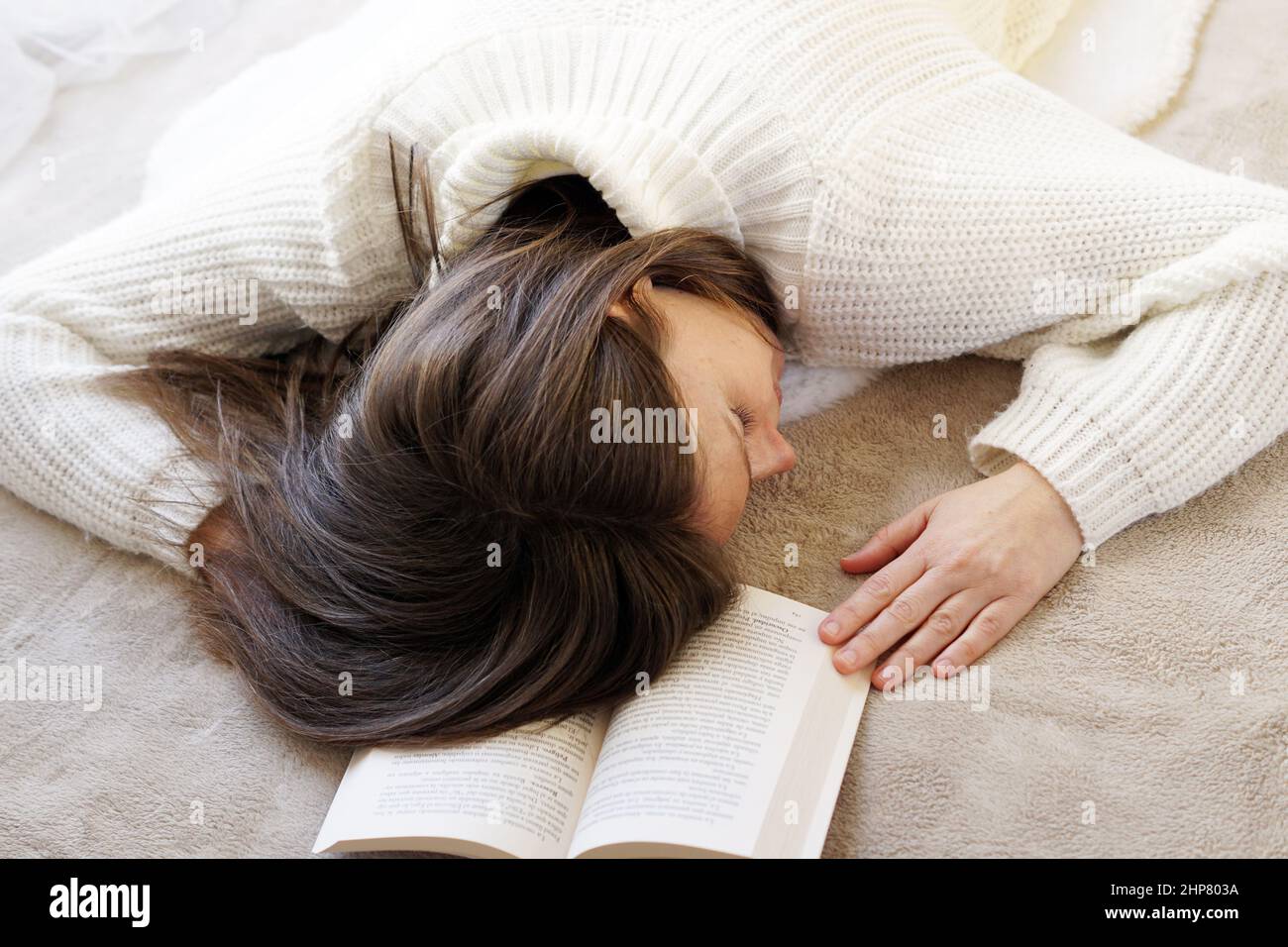 Woman with a warm sweater sleeping on the floor after reading a book at ...