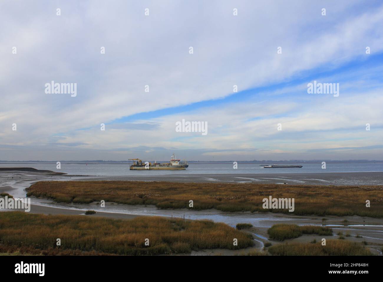 a dutch coast landscape with a hopper dredger and ship in the ...