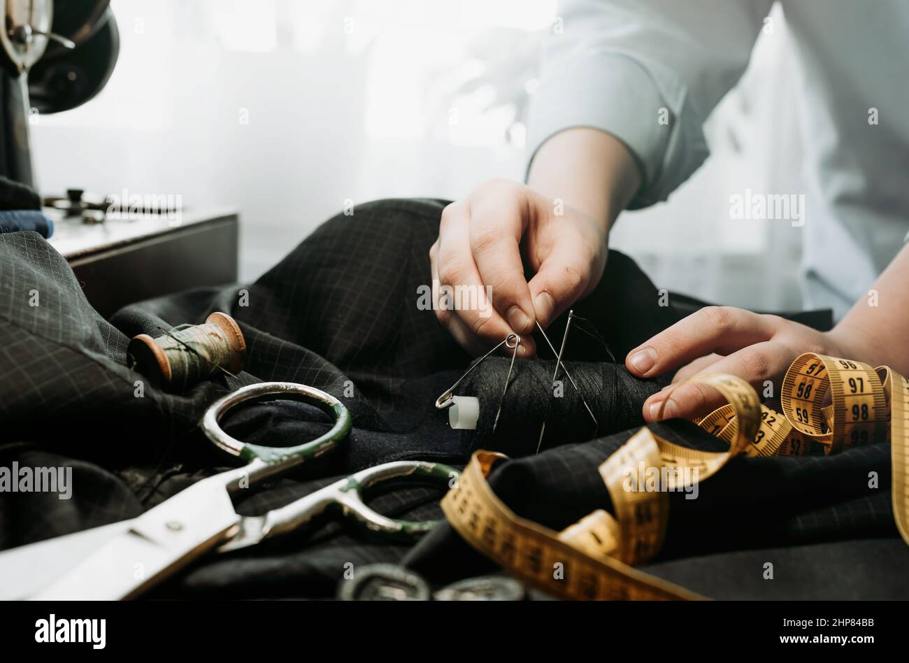 The tailor's hands sew clothes with a needle and thread. Tools for a ...