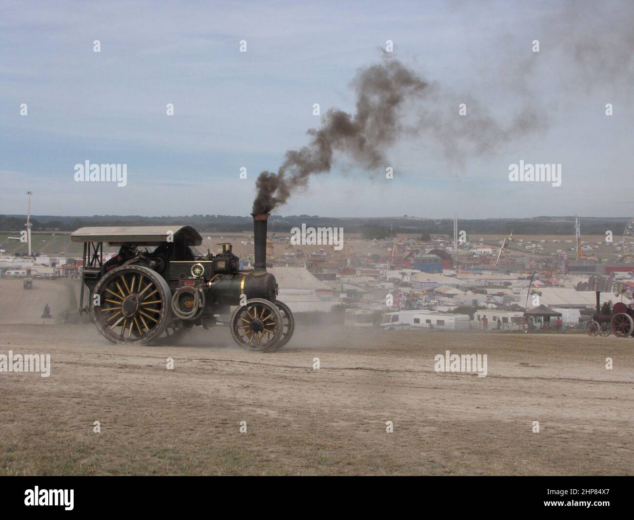 a historical steam tractor engine with a big plume of smoke is driving ...