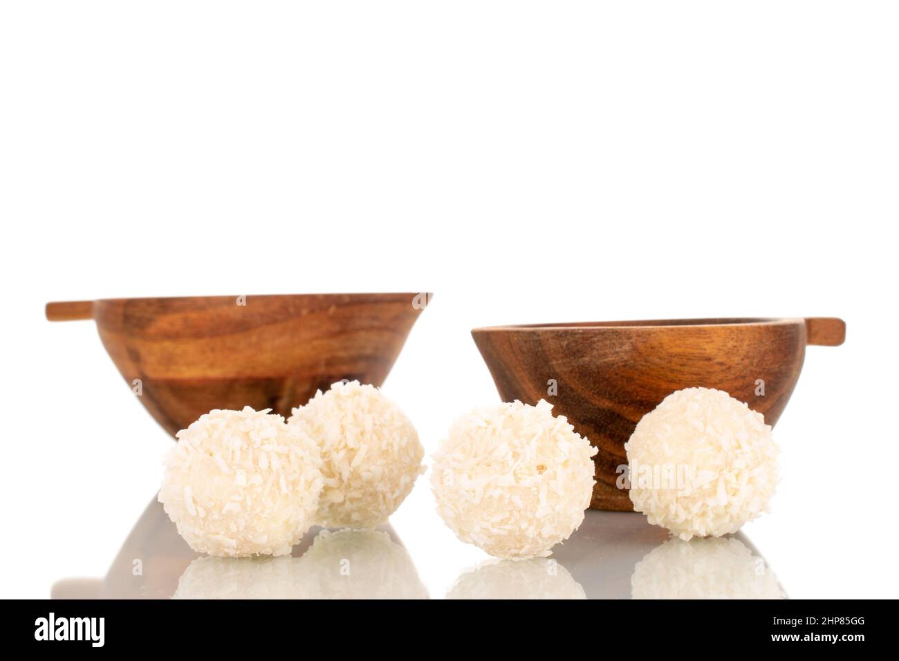 Some sweet coconut candy with two wooden cups, macro, isolated on a ...